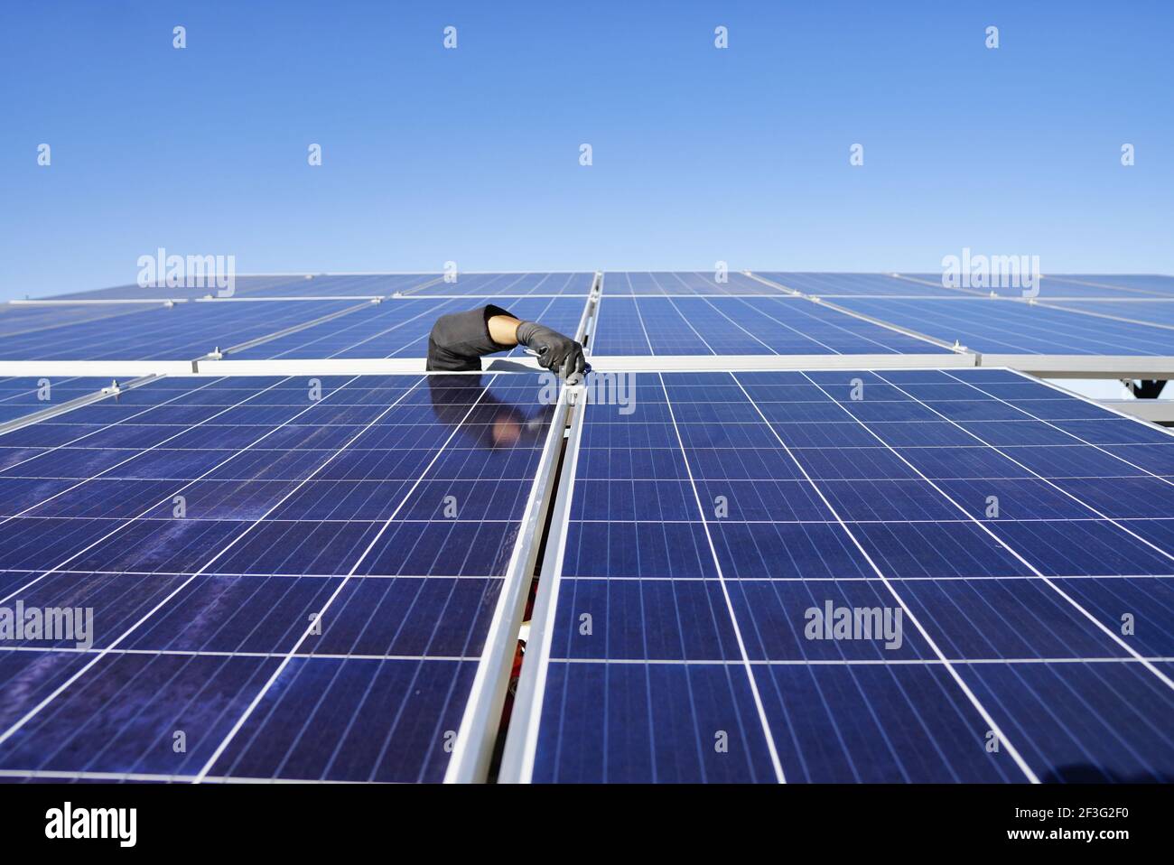 A person working on the solar panels on a roof under the sunlight at ...