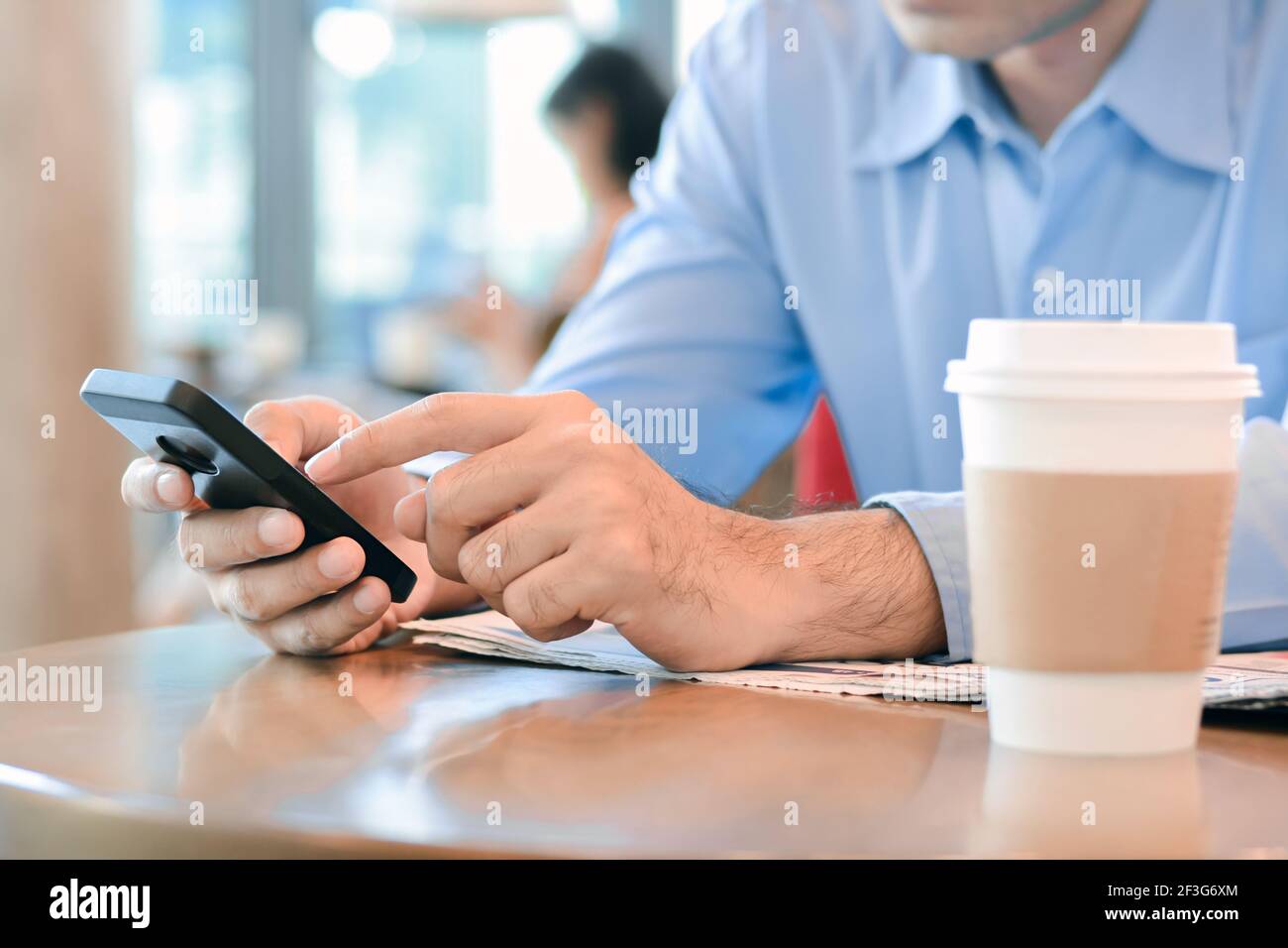 A man using smart phone with coffee cup on the table in coffee shop ...