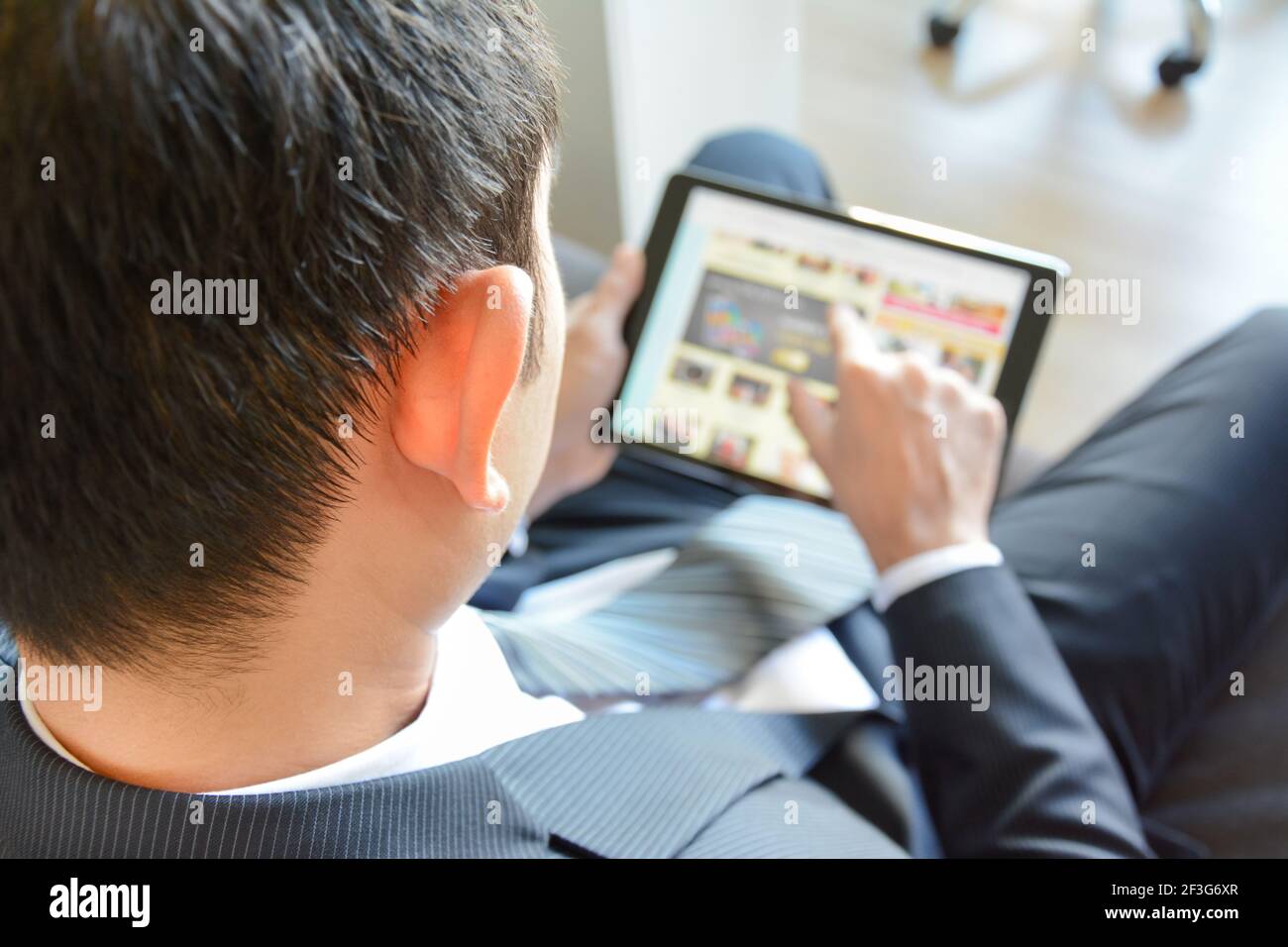 Businessman using tablet computer while sitting on the couch - over ...