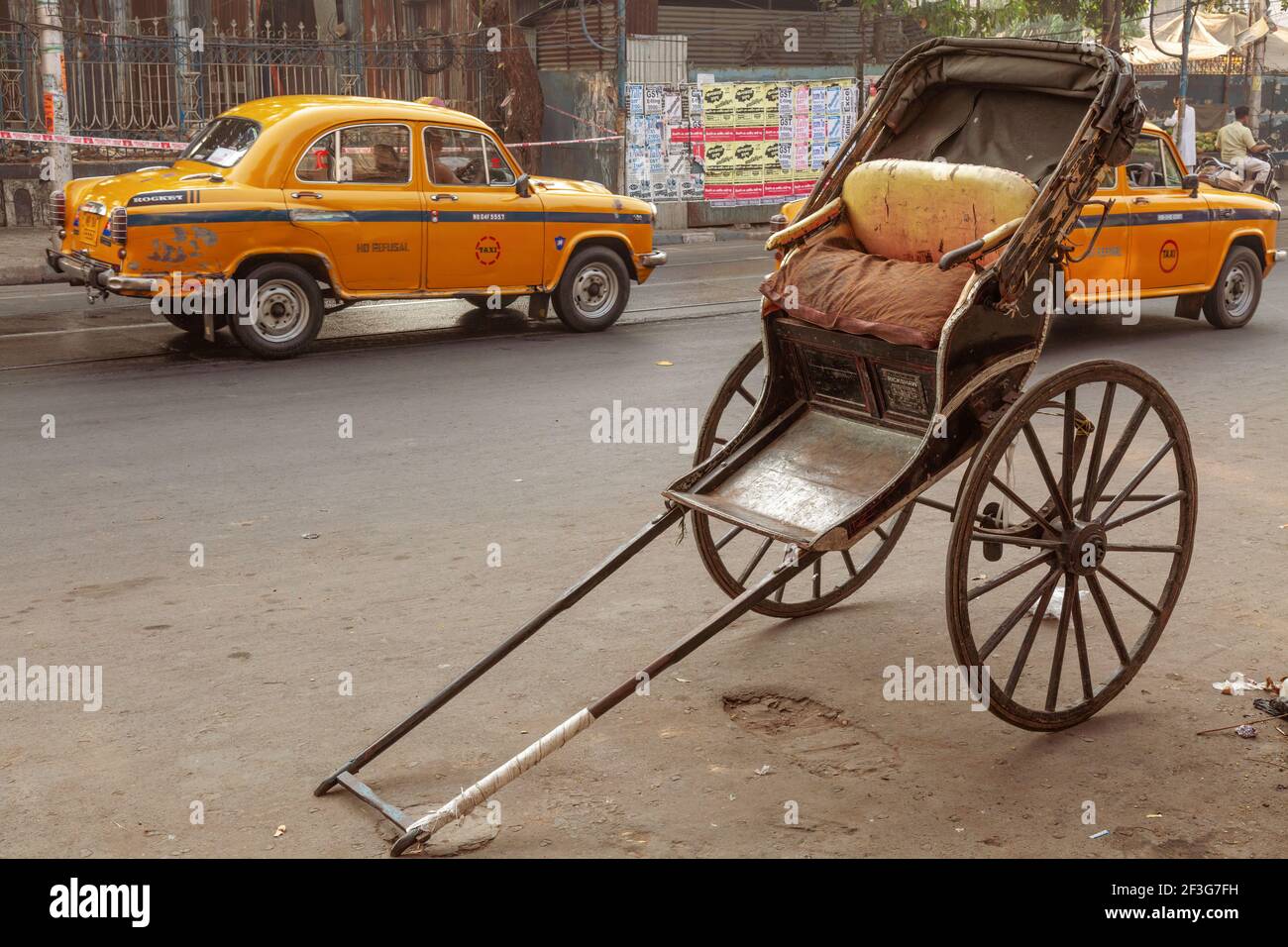 Hand drawn rickshaw with view of yellow taxi on city road at Kolkata ...