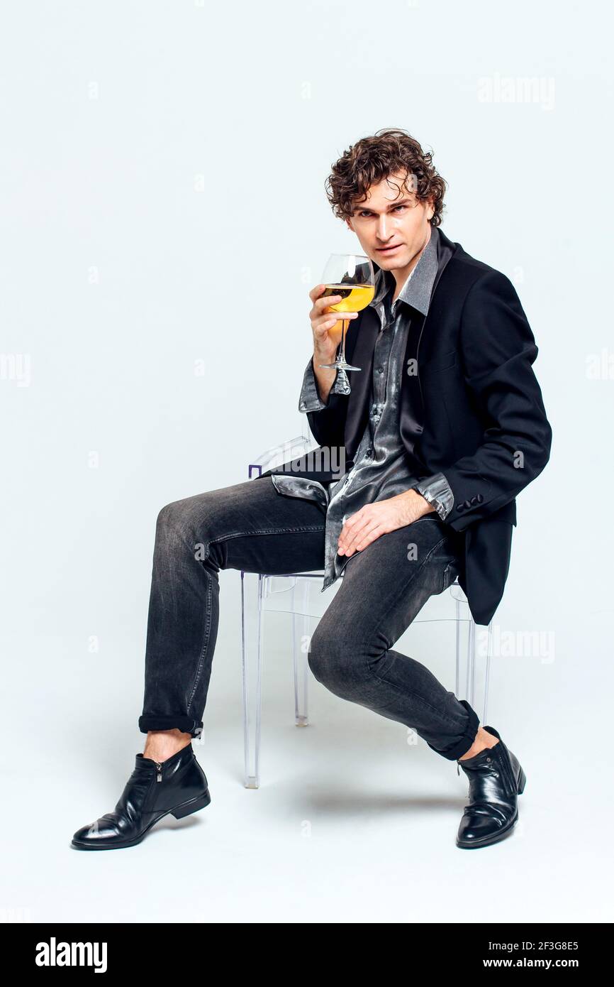 Tall handsome confident young man in a jacket sitting on the chair and ...