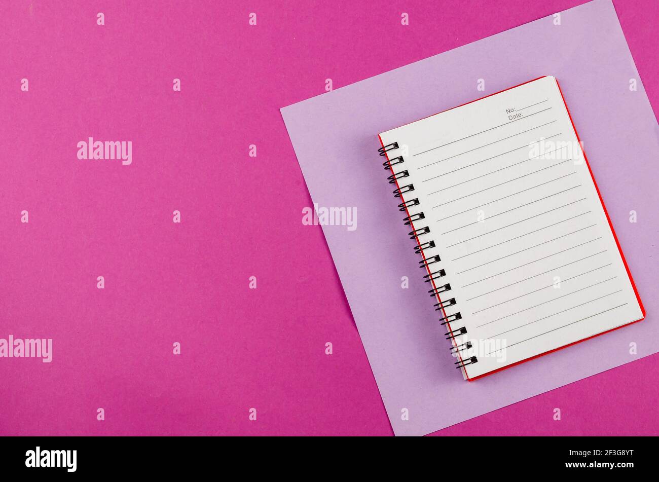 Open spring-loaded notebook on a pink and lilac background. White ...