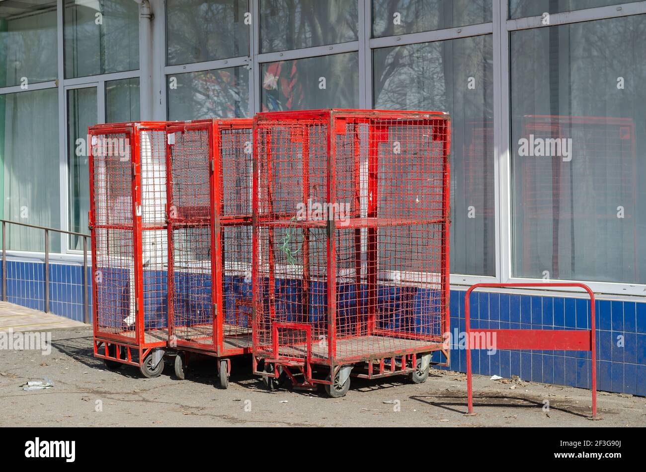 Red cages on wheels outside the building. Storage cages against a glass ...