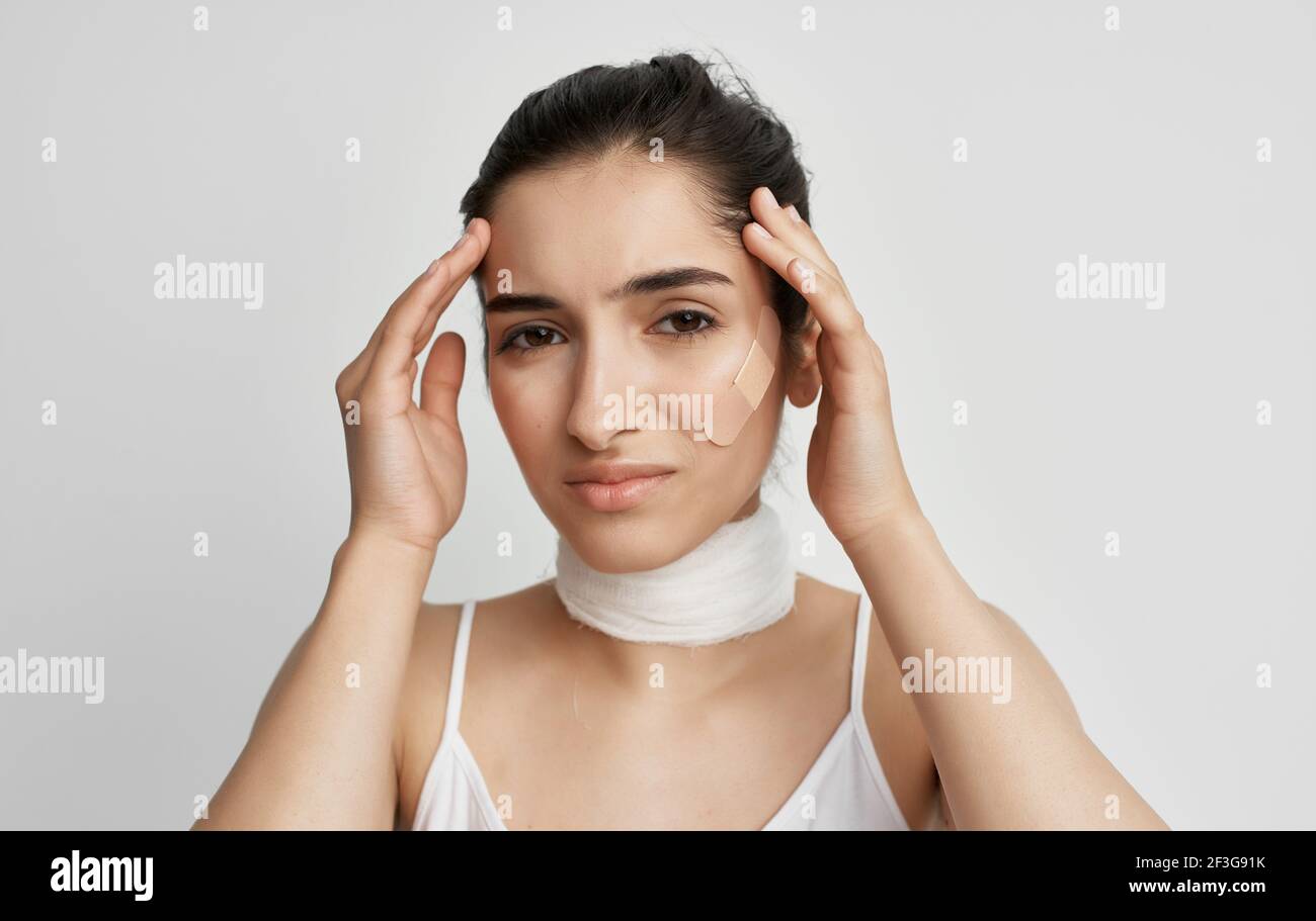 brunette with a bandaged neck holding her head health problems Stock ...