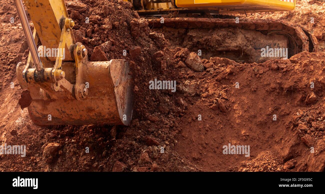 Backhoe working by digging soil at construction site. Bucket of backhoe ...