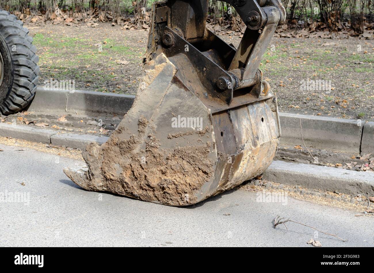 Repair and restoration work on a city street. Dirty bucket excavator ...