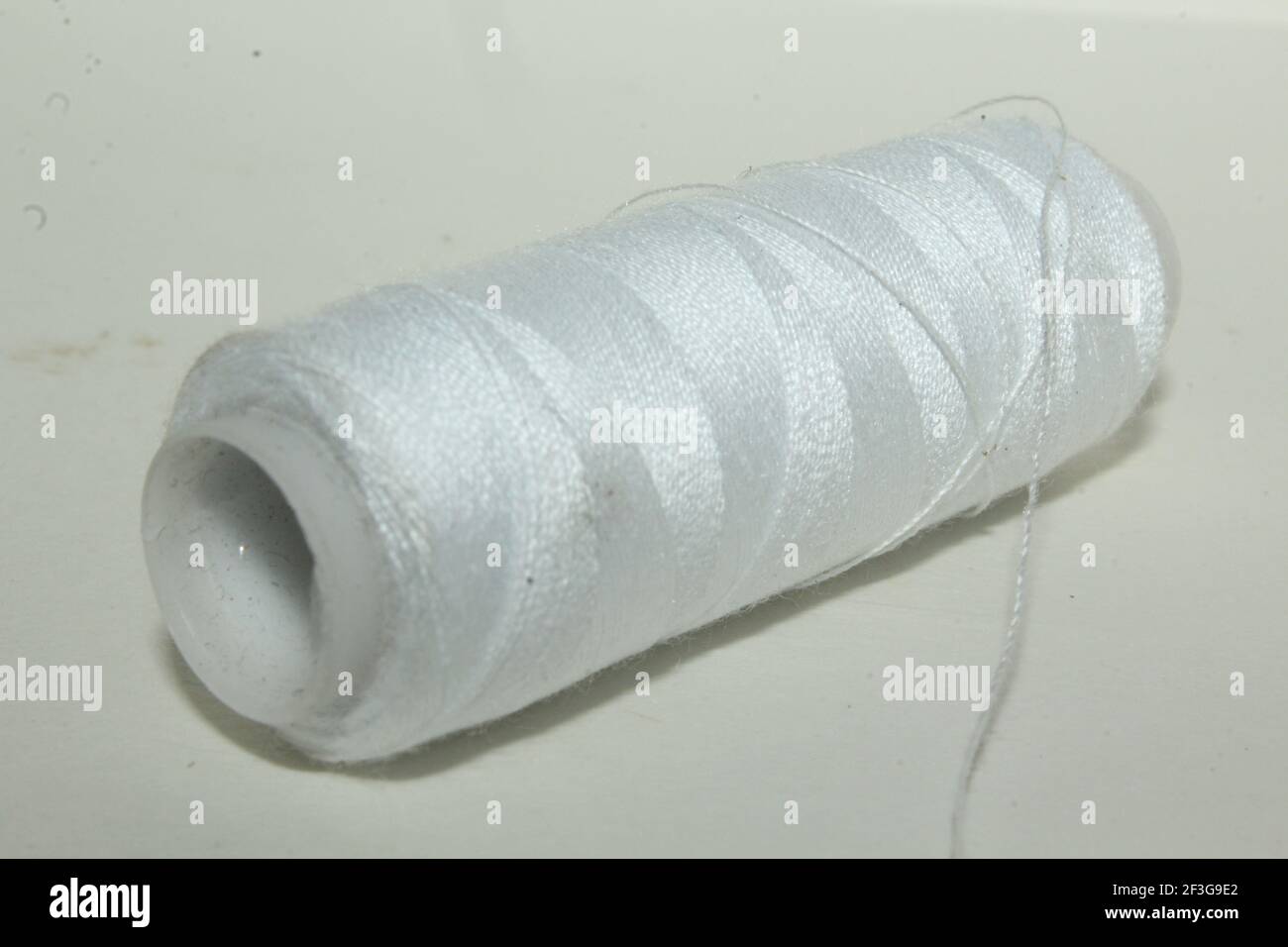 Reel of white thread on white background Stock Photo - Alamy