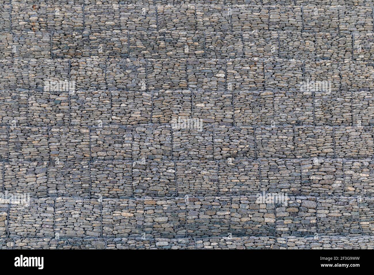 Wall texture assembled from blocks of river stones in a metal mesh ...