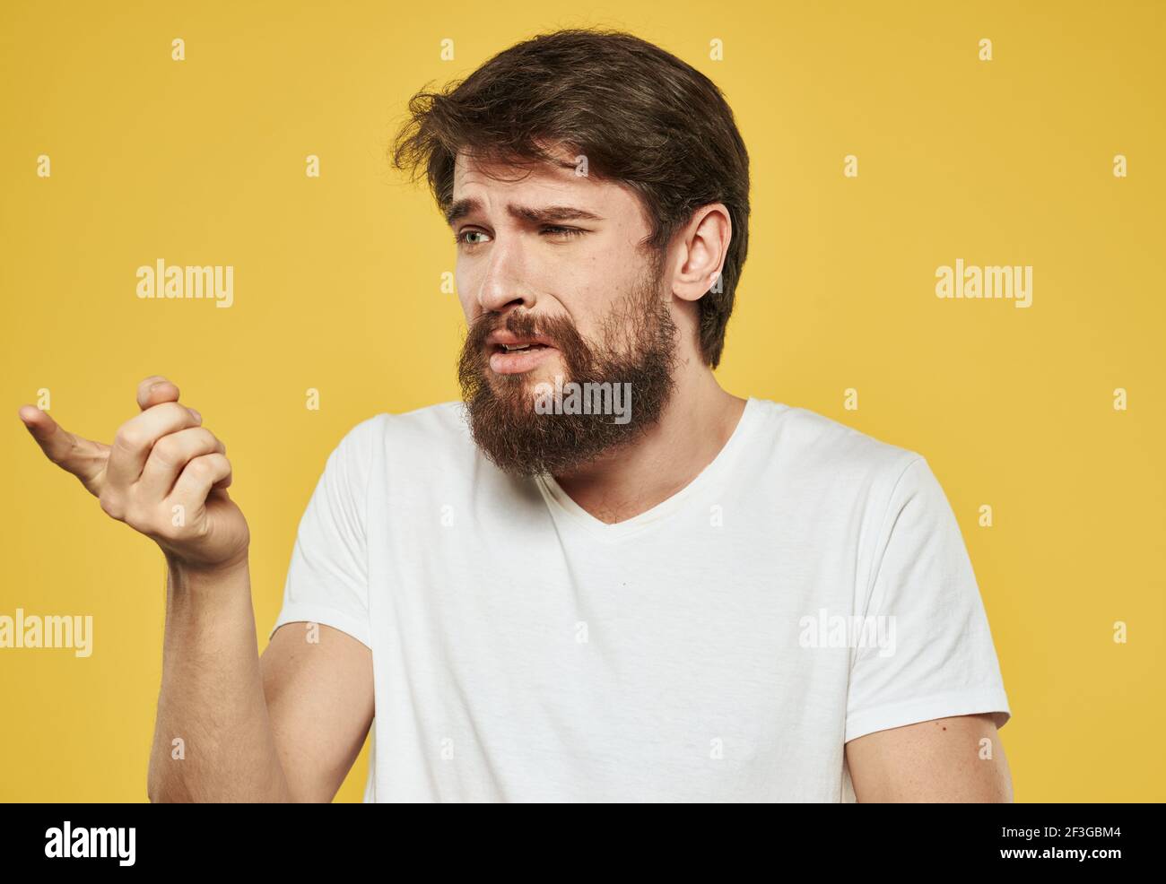Upset guy crying on a yellow background and gesturing with his hands ...