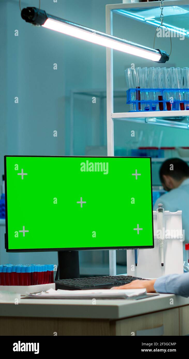 Microbiologist working on computer with display, green chroma key ...