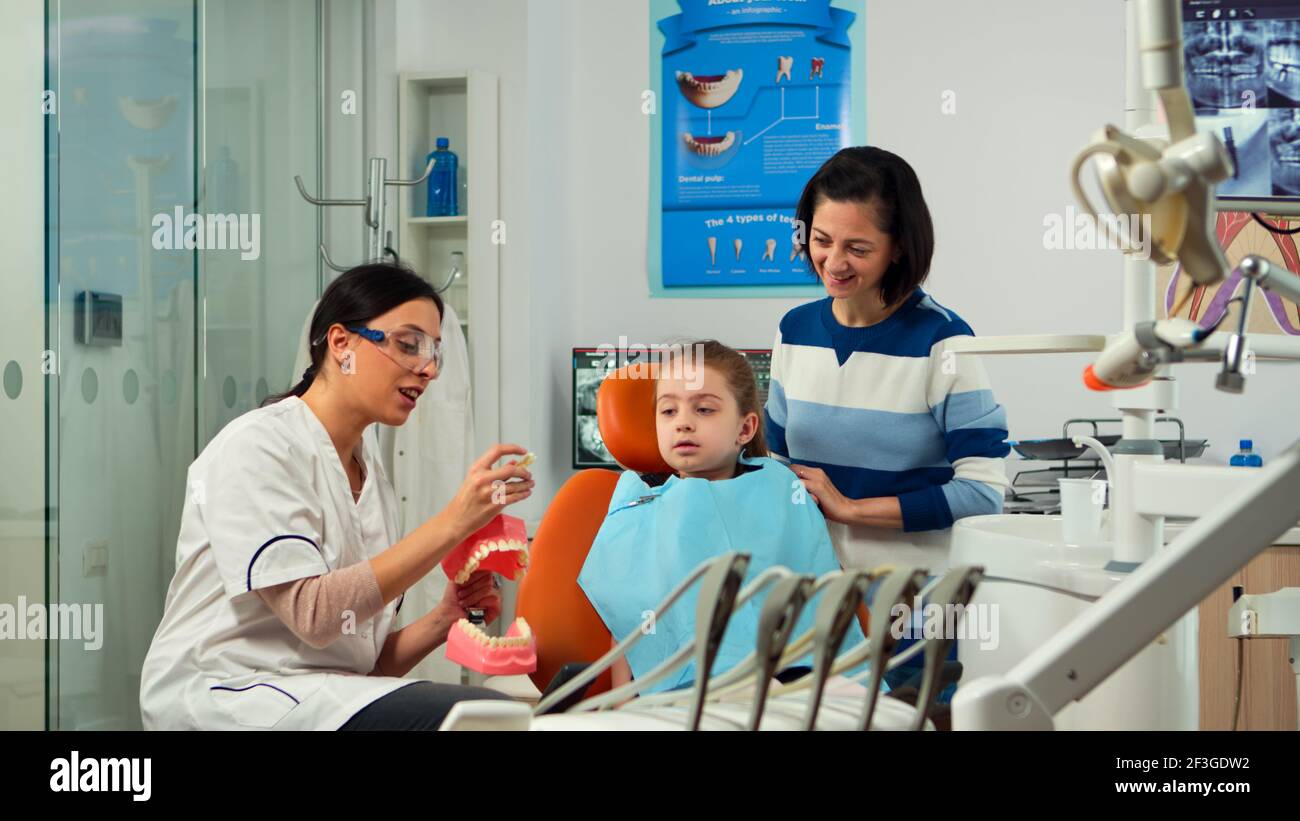 Stomatologist explaining proper dental hygiene using presentation teeth ...