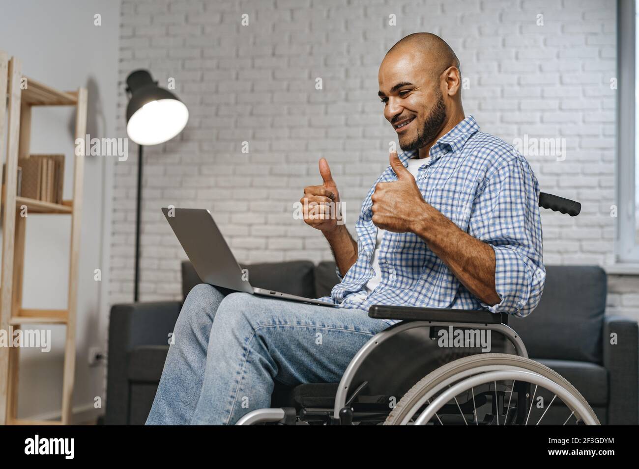 Disabled man sitting in a wheelchair and using laptop Stock Photo - Alamy