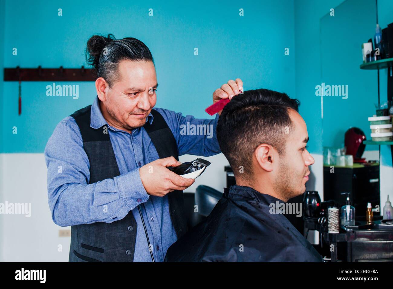 latin man stylist cutting hair to a client in a barber shop in Mexico ...