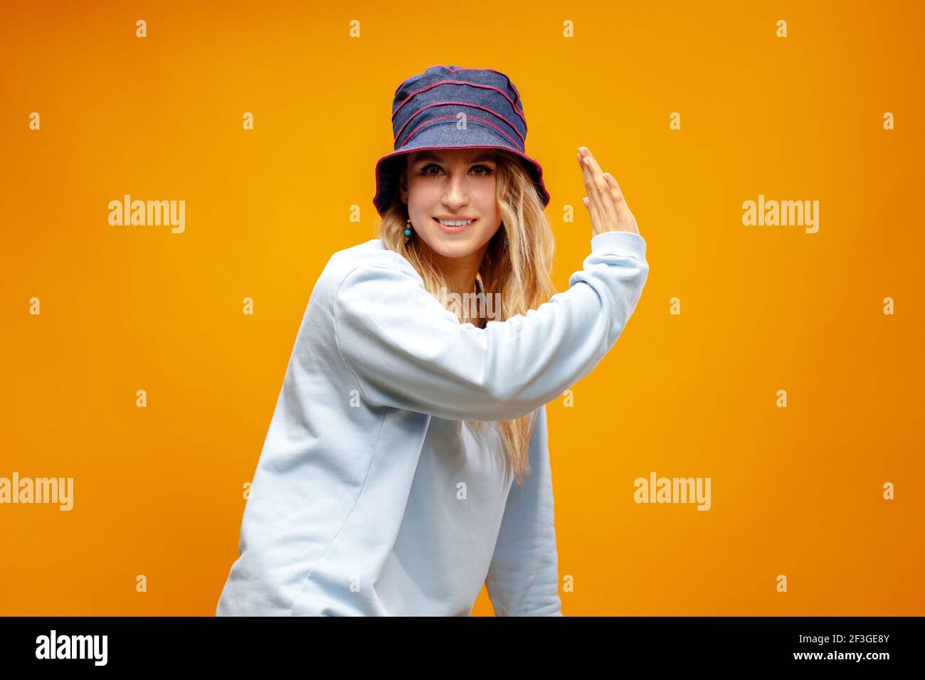 Stylish girl in panama hat dancing against yellow background Stock ...