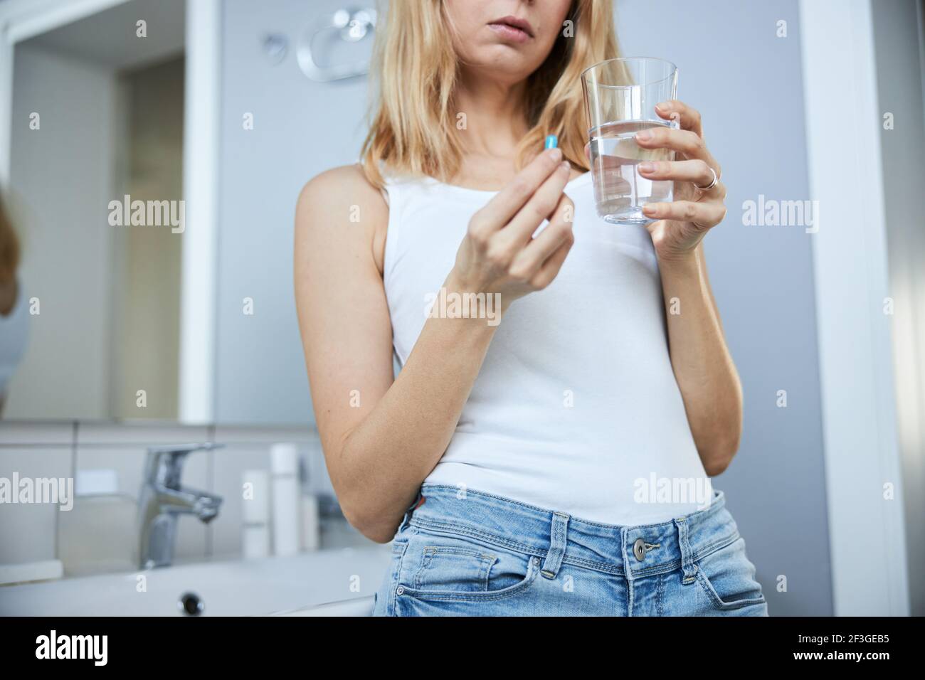 Young woman taking pill in bathroom at home Stock Photo - Alamy