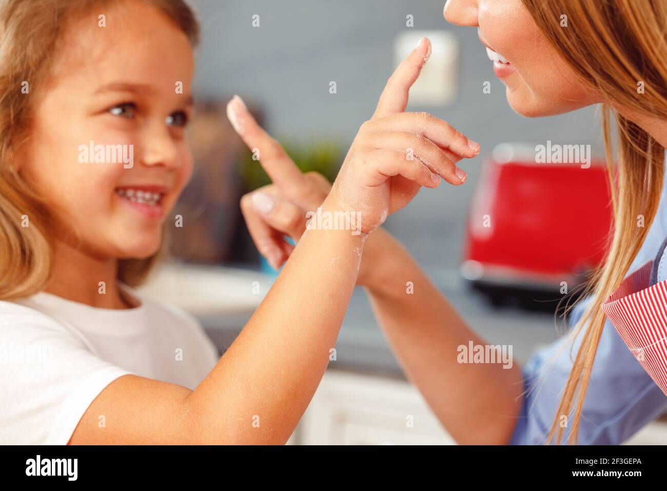 Little girl and her mother stain each other noses with flour Stock ...