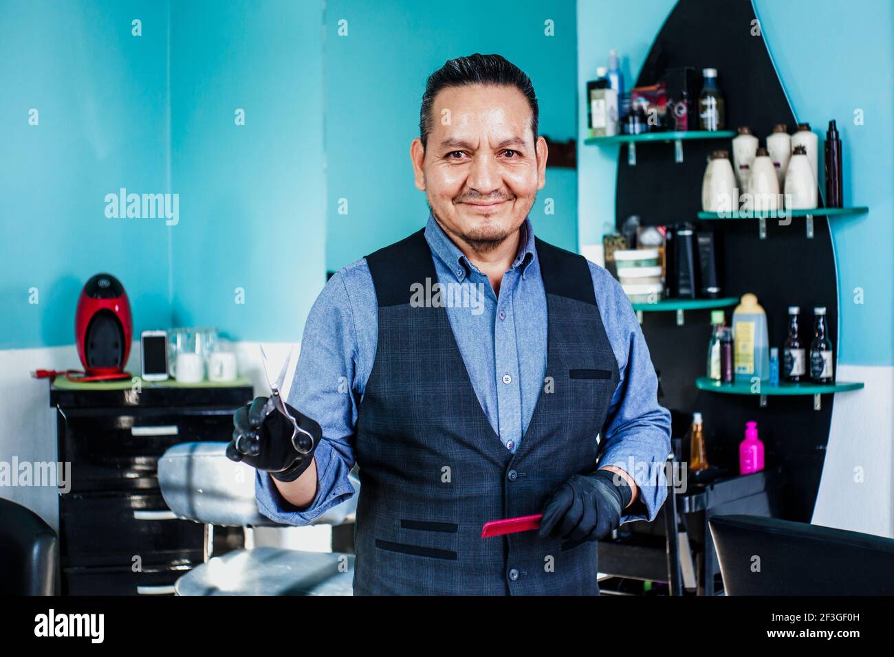Portrait of latin man barber holding equipments in hand, looking at ...