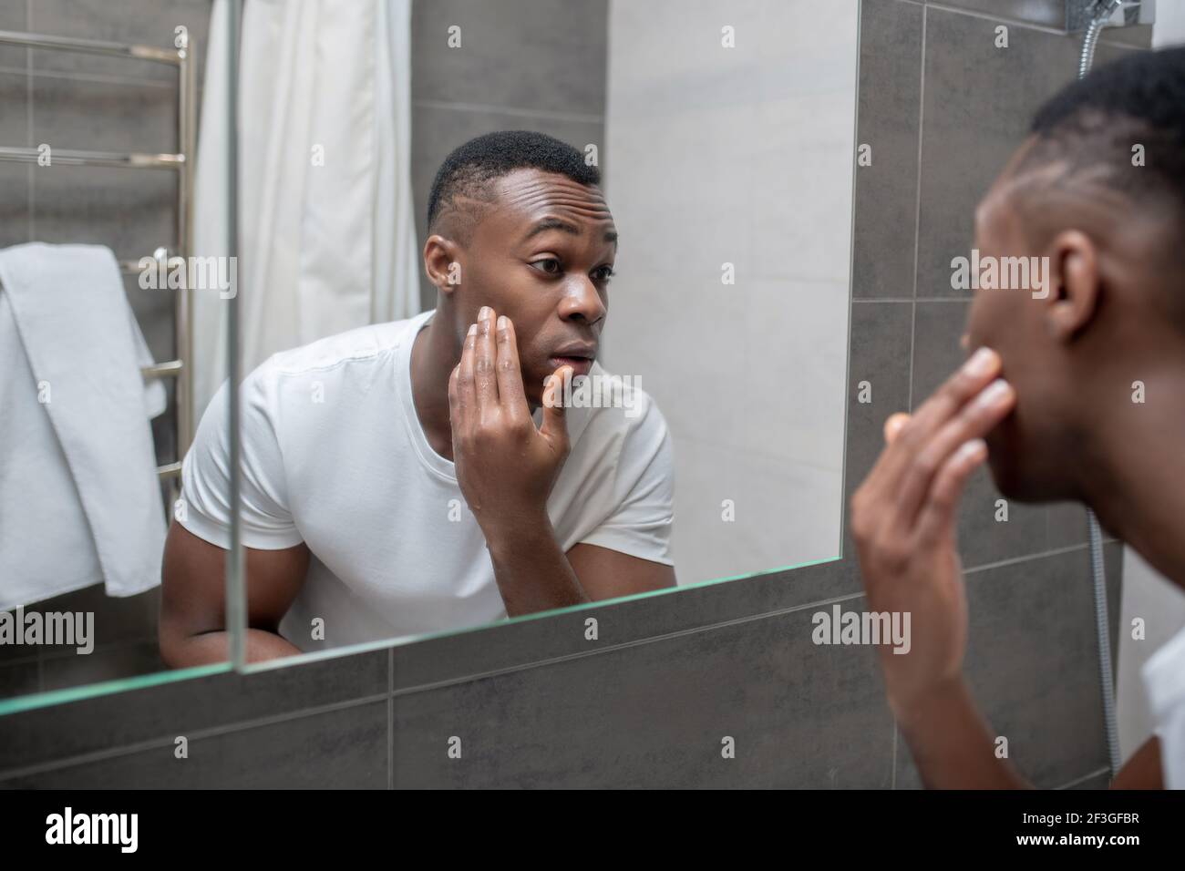 Dark-skinned young handsome man looking at himself in the mirror Stock ...