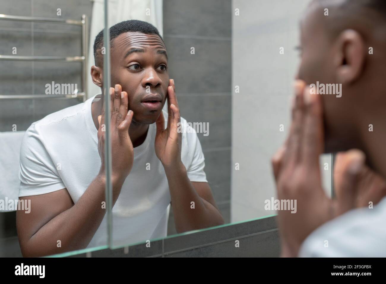 Dark-skinned young handsome man looking at himself in the mirror Stock ...
