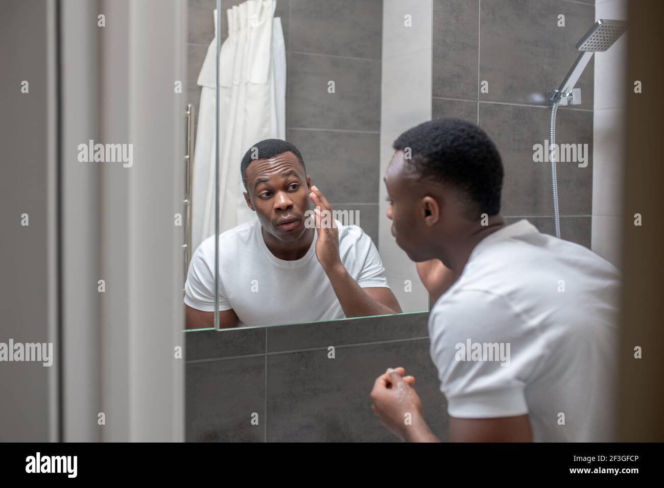 Dark-skinned young handsome man looking at himself in the mirror Stock ...