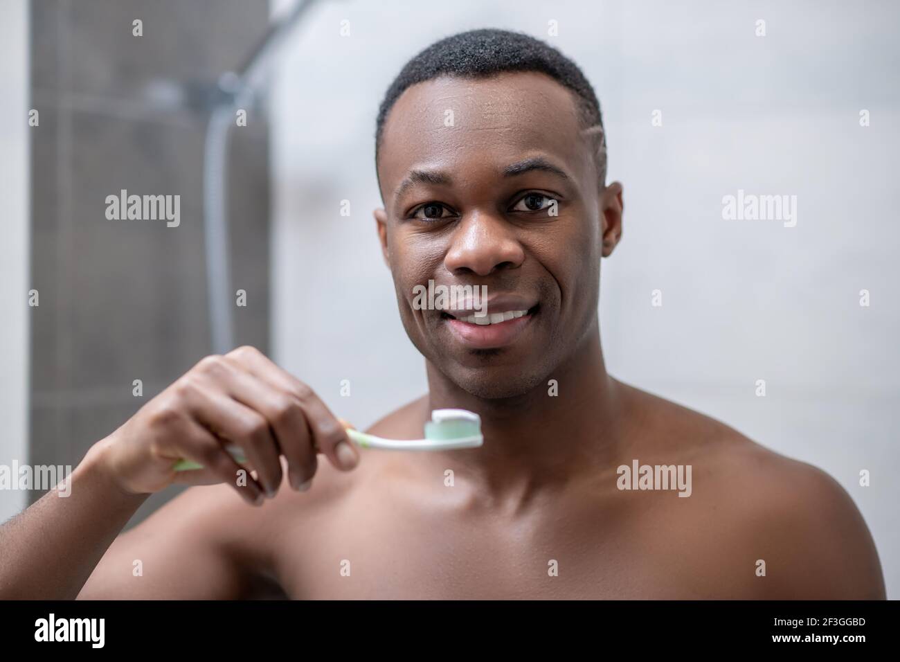 African american short-haired guy looking at himself in the mirror ...