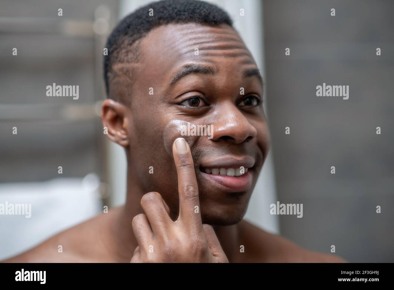 African american short-haired guy applying some cream on his face Stock ...