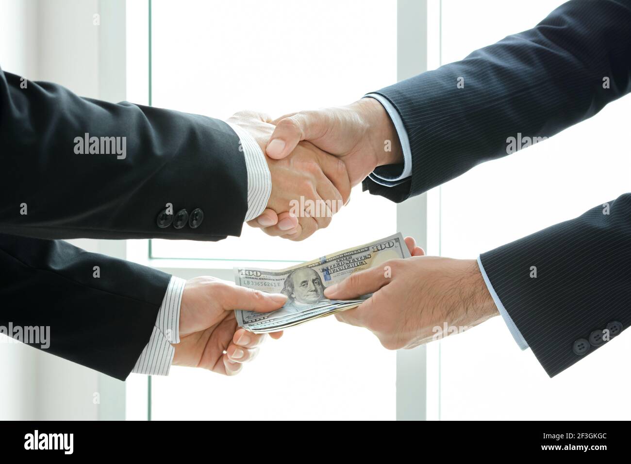 Businessmen making handshake while passing money - dealing & bribery ...