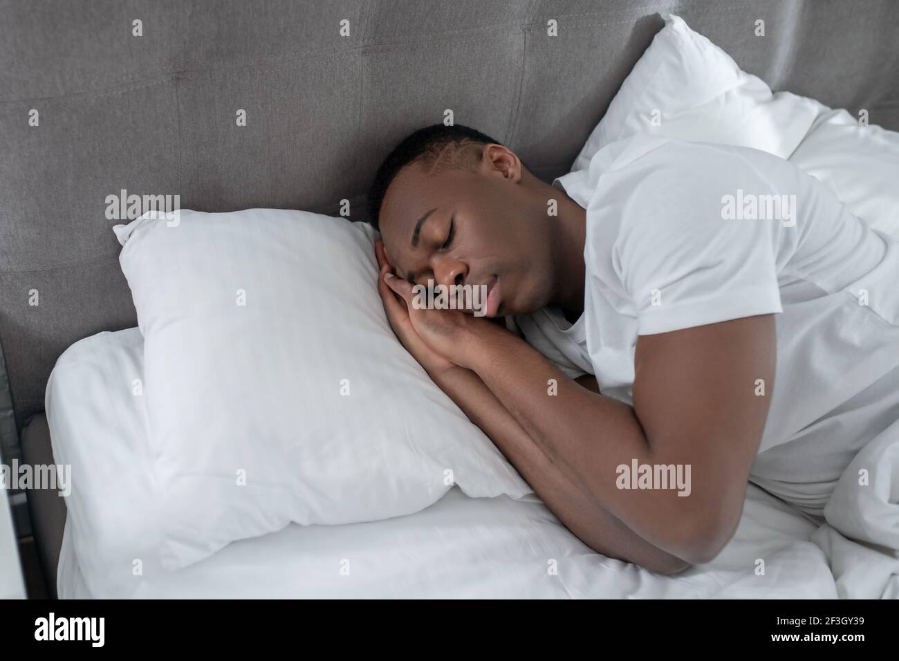 A young man in white sleeping and looking peaceful Stock Photo - Alamy