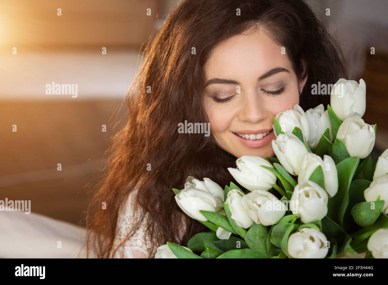 Closeup portrait of a beautiful young woman holding big bunch of white ...