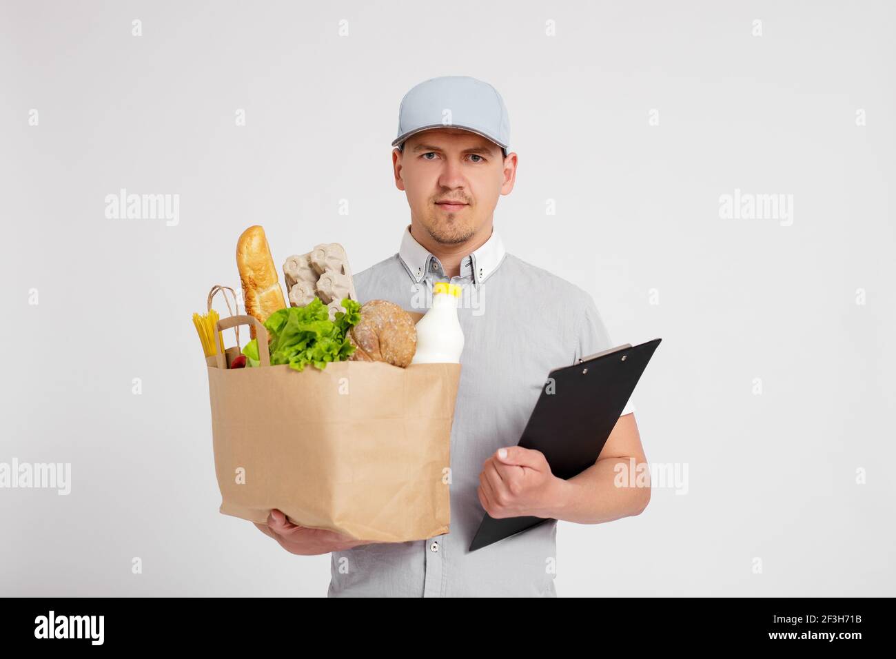 food delivery concept - delivery man in uniform with paper bag full of ...