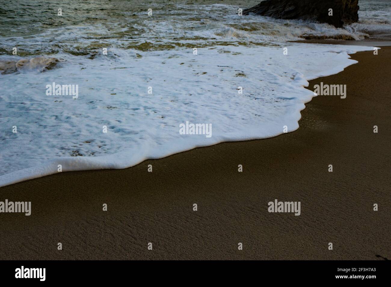 Atlantic storm waves crashing up and washing over rocks and sand on the ...