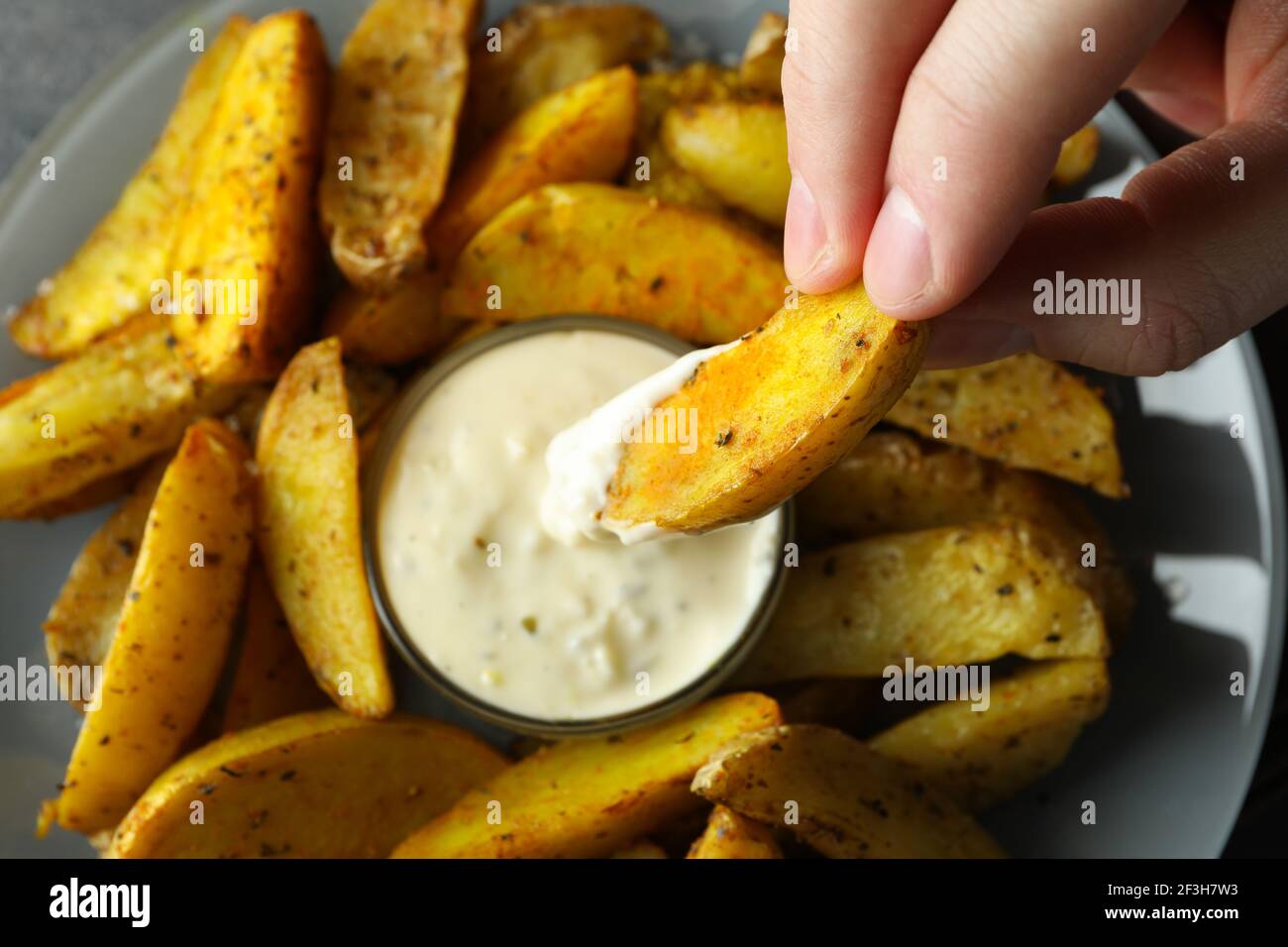 Female hand dip potato wedge in sauce, close up Stock Photo - Alamy