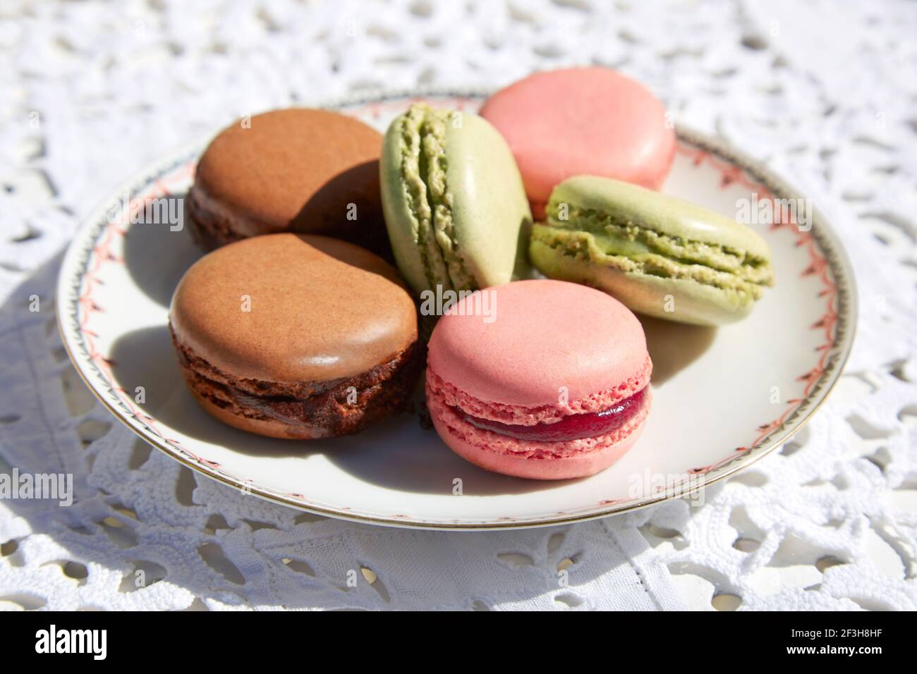 Macarons cookies with ceramic saucer and white embroidered tablecloth ...
