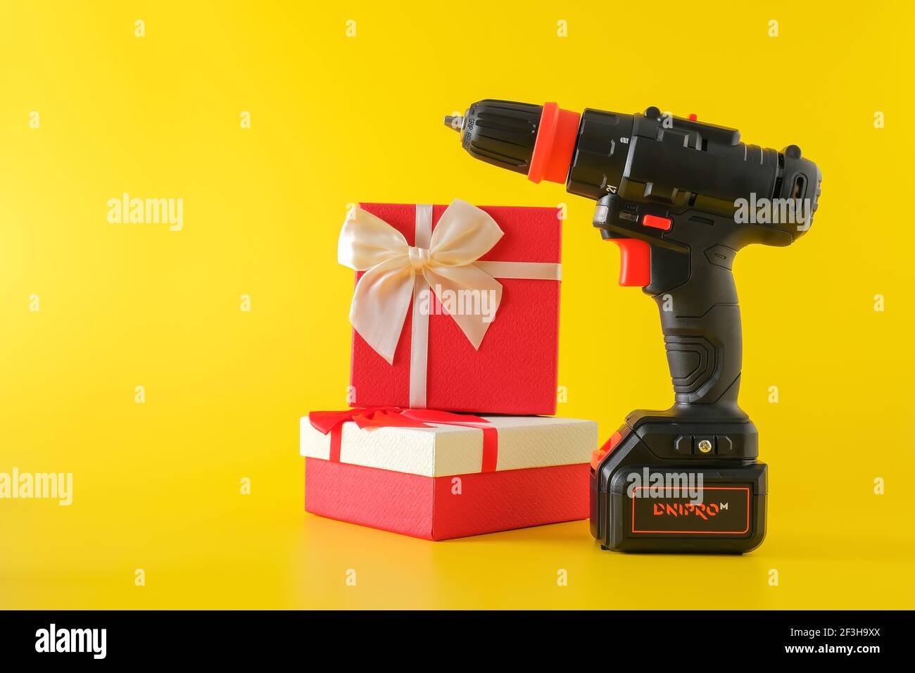 Handheld cordless power drill and gift boxes on yellow background Stock ...
