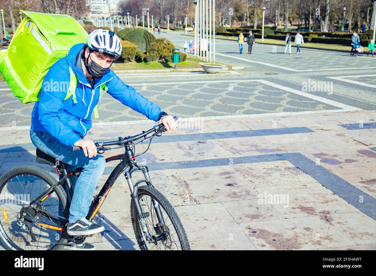 Delivery man riding bike wearing mask Stock Photo - Alamy