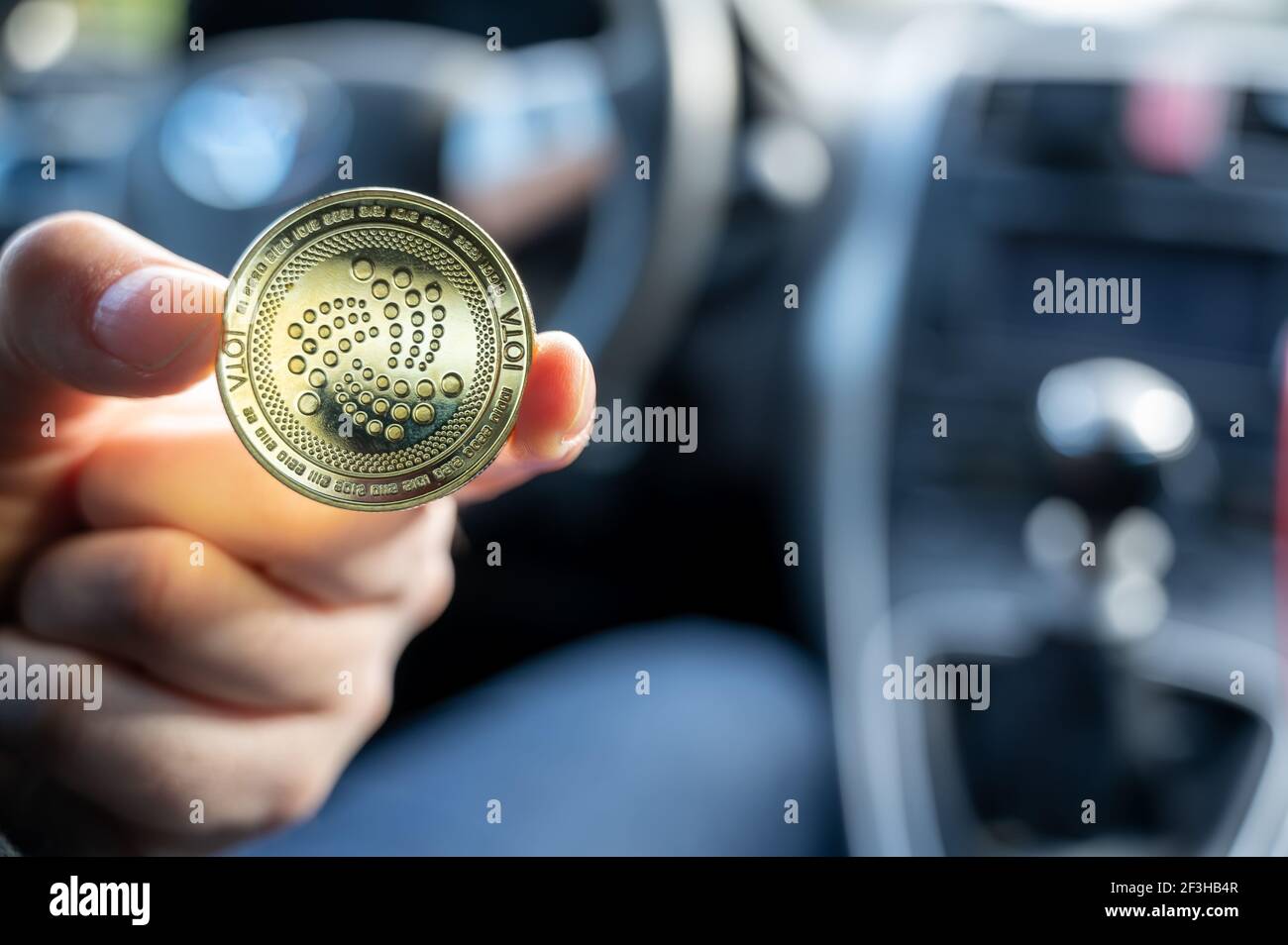 Symbol for autonomous driving. Hand holds a IOTA coin in a self driving ...