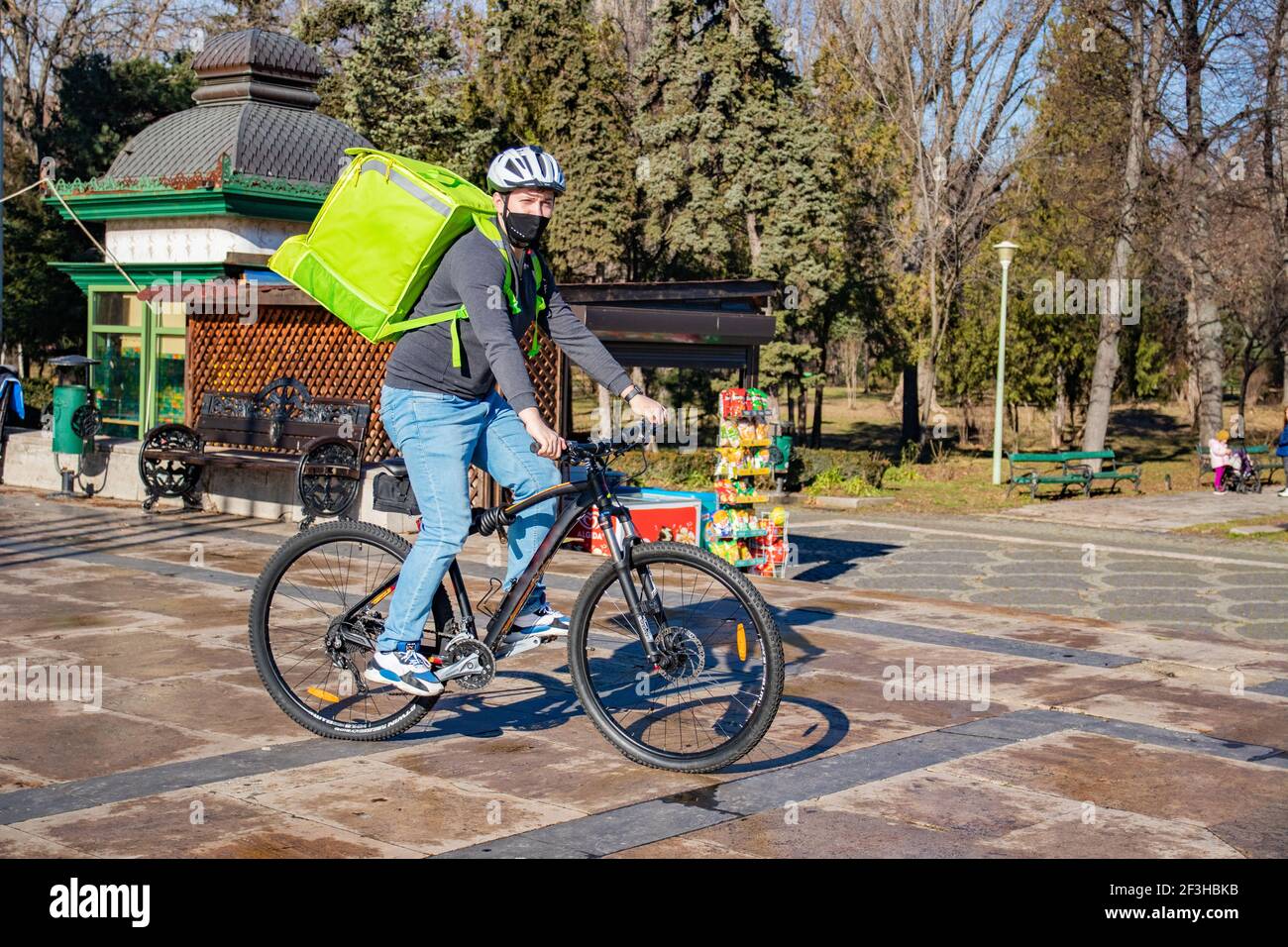 Delivery man riding bike wearing mask Stock Photo - Alamy