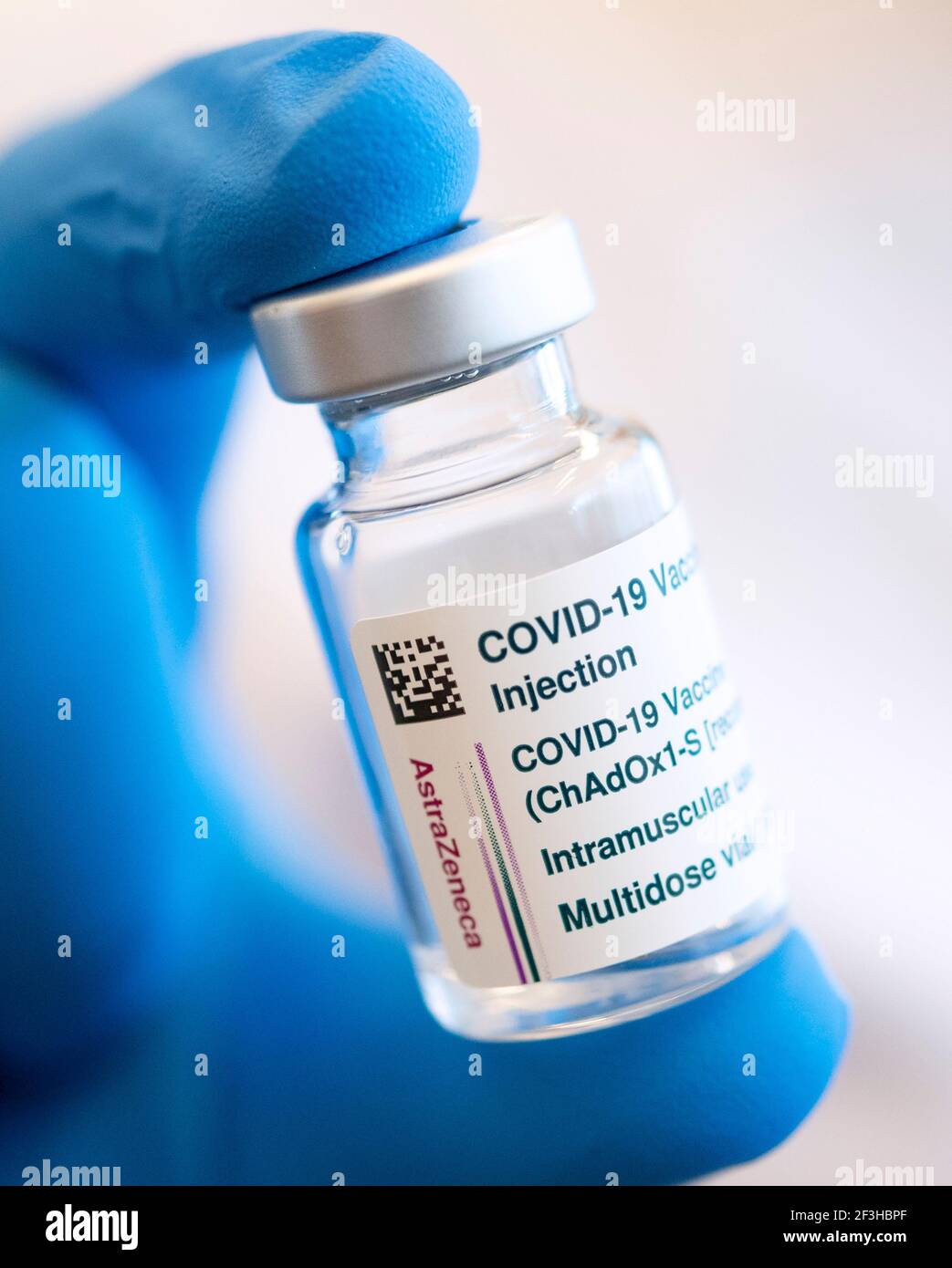 A gloved hand holding a vial / bottle of AstraZeneca covid-19 vaccine ...