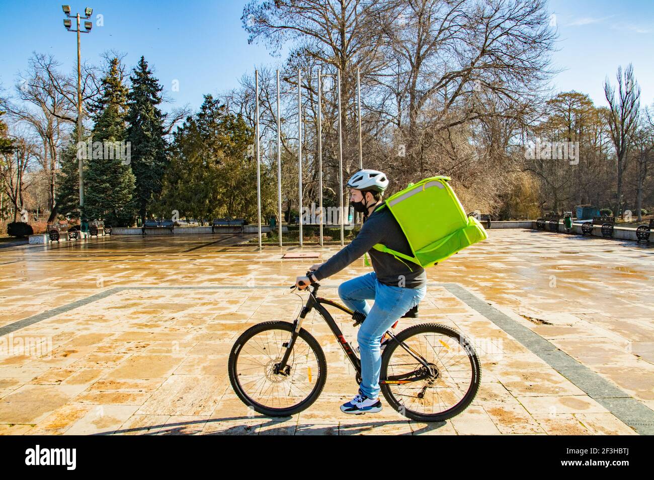 Delivery man riding bike wearing mask Stock Photo - Alamy