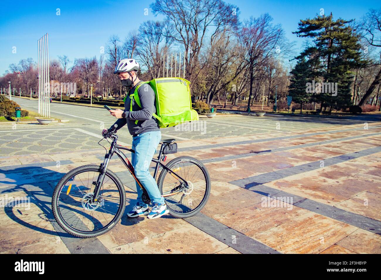 Delivery man riding bike wearing mask Stock Photo - Alamy