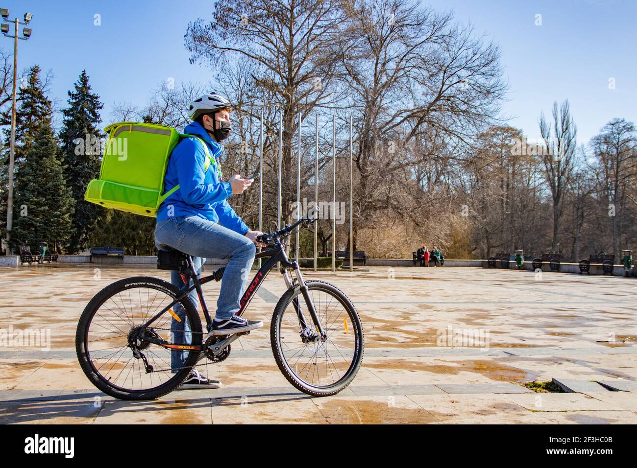 Delivery man riding bike wearing mask Stock Photo - Alamy