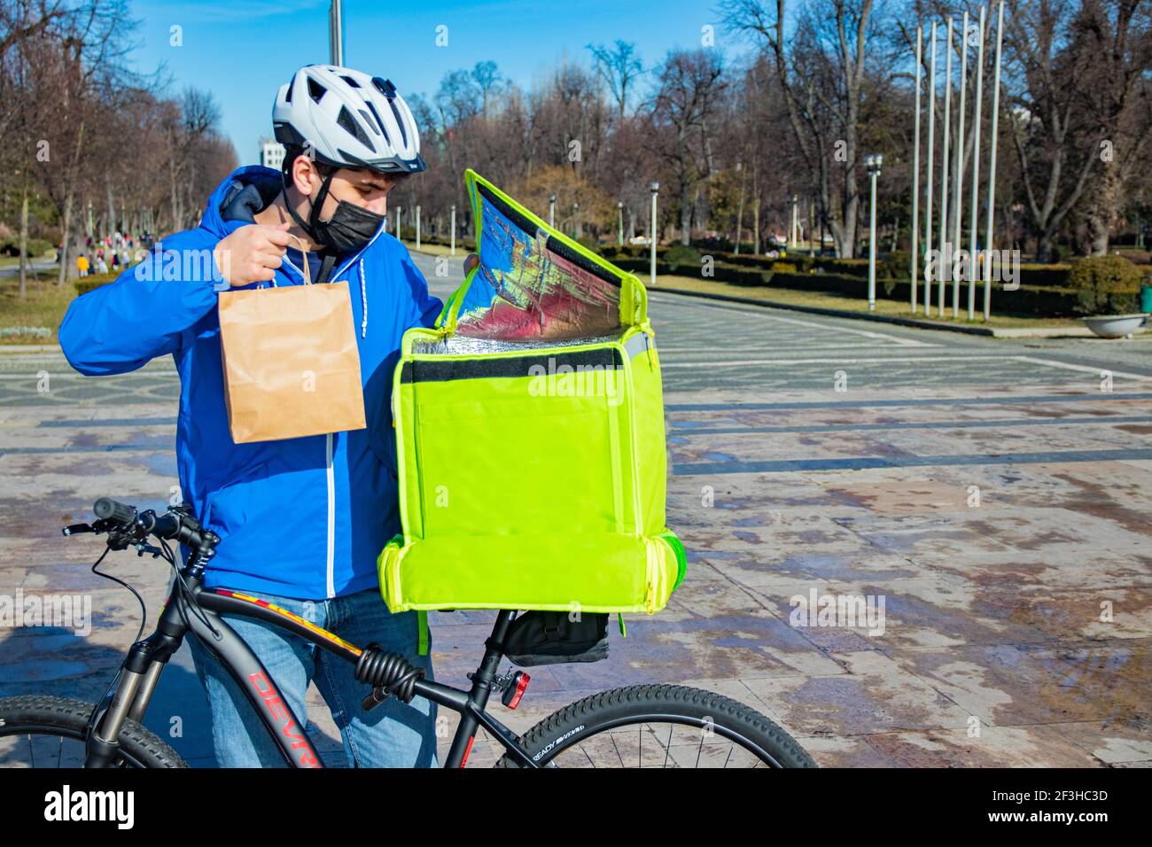 Delivery man riding bike wearing mask Stock Photo - Alamy