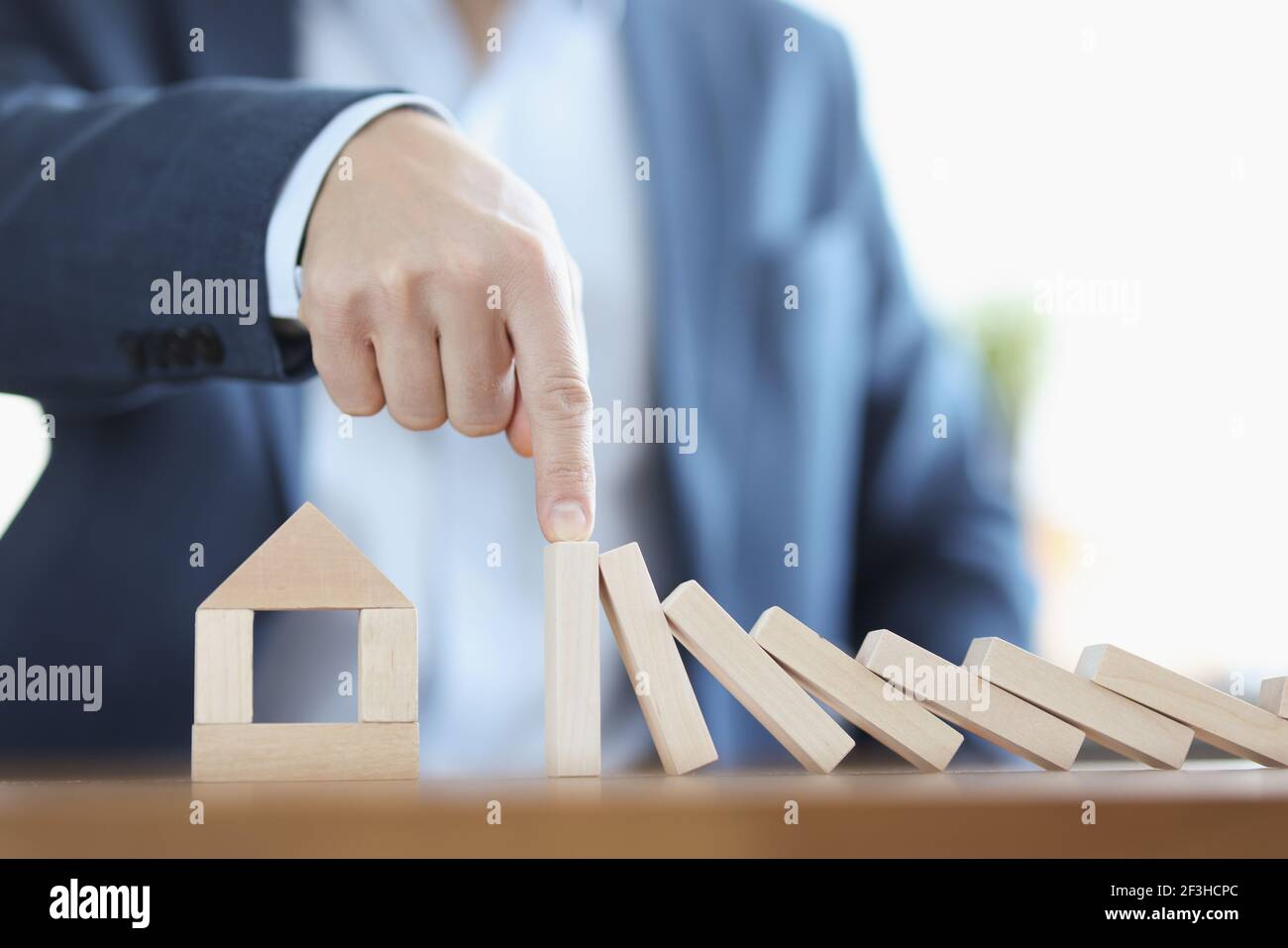 Businessman holds falling figurines of wooden blocks on house Stock ...