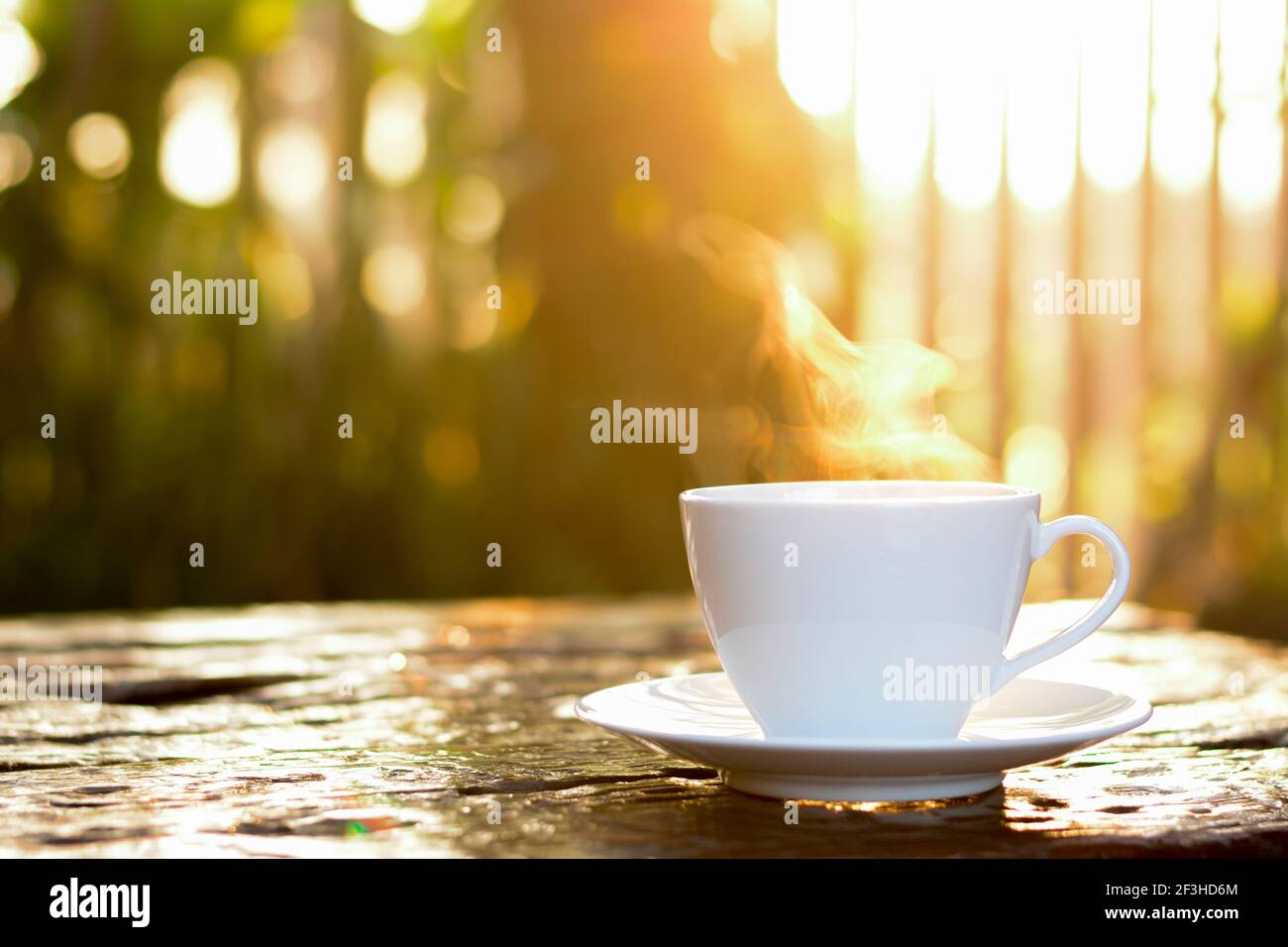Hot coffee in the cup on old wood table with sunlight & blur green ...
