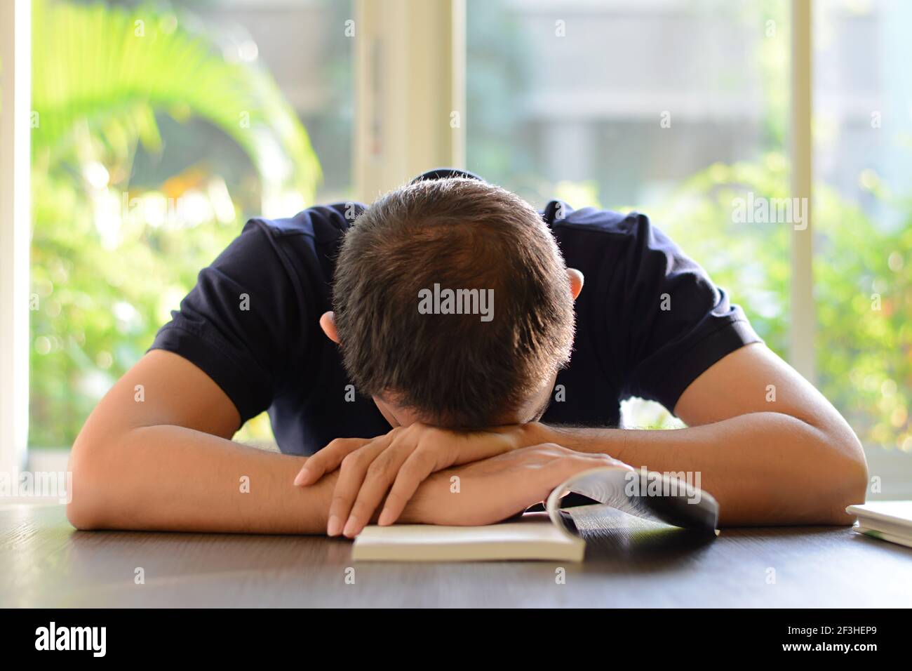 Young man sleeping on the table with book opened, weary & tired of ...