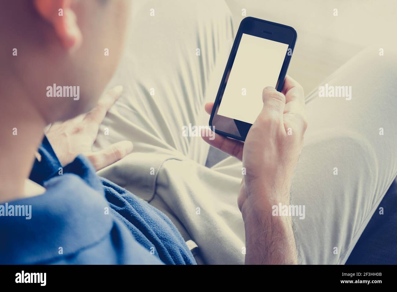 A man looking at smart phone with blank screen while sitting - vintage ...