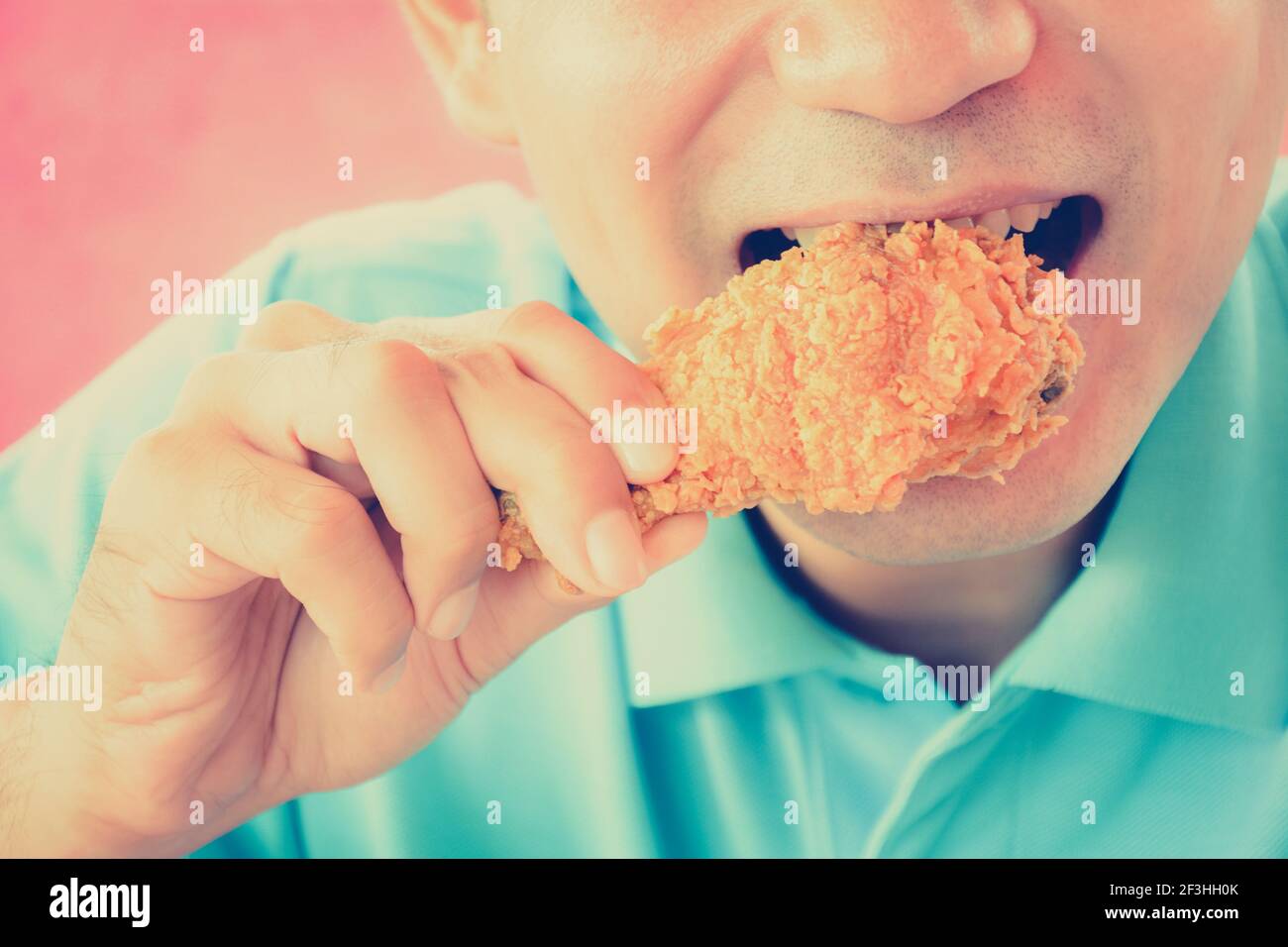 A man biting deep fried chicken leg or drumstick - vintage style color ...