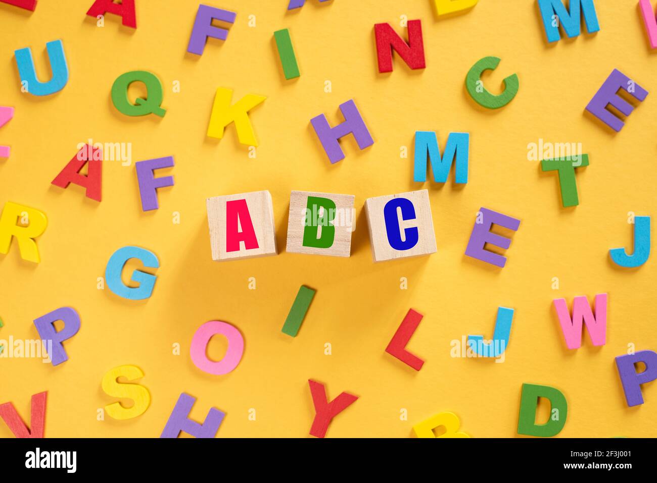 Alphabet on wooden tiles and ABC on a cube against yellow background ...