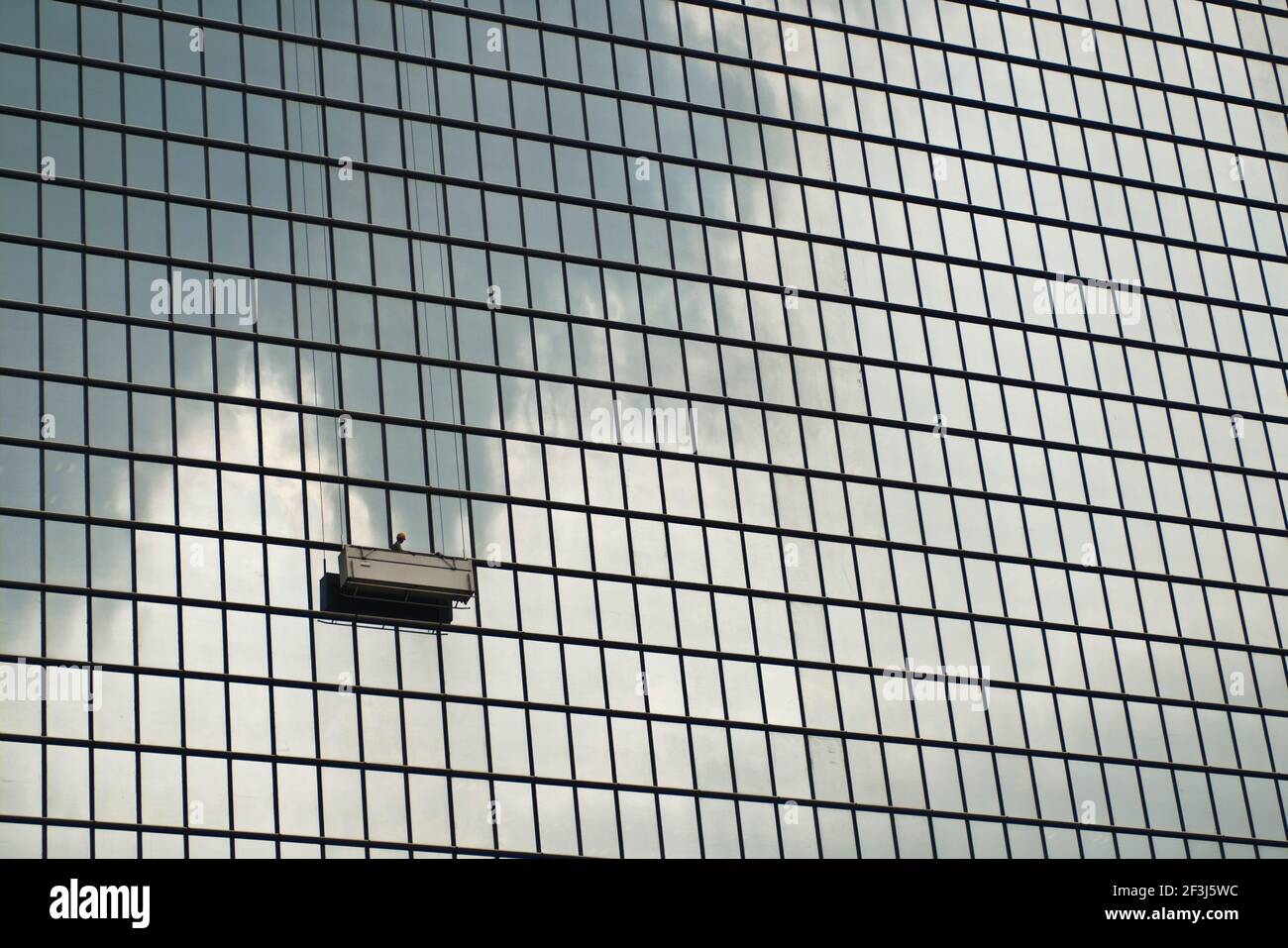 View of man in window-cleaning gondola on the glass facade of the ...