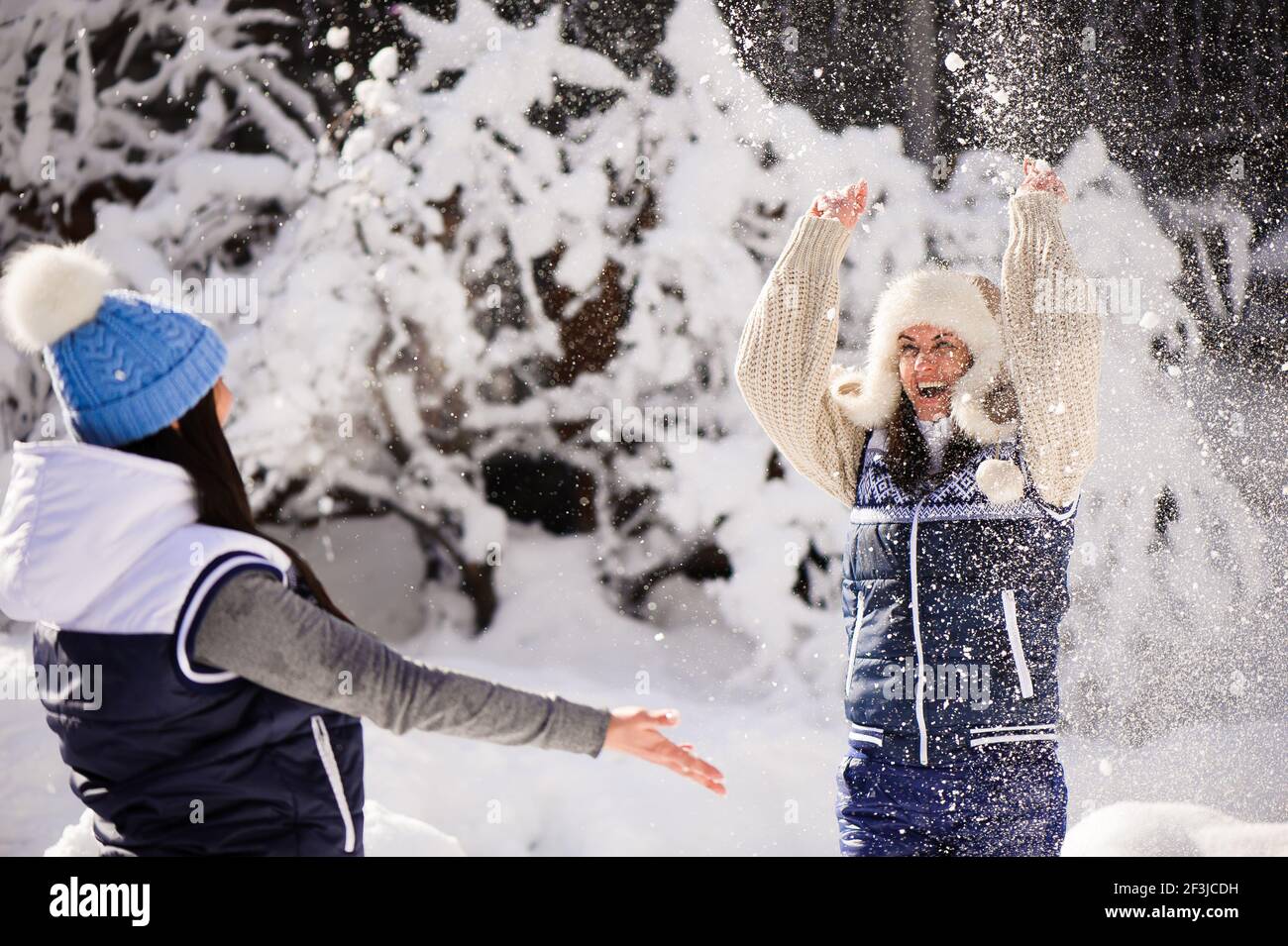 Two sisters playing with snow and having fun winter time, best friends ...